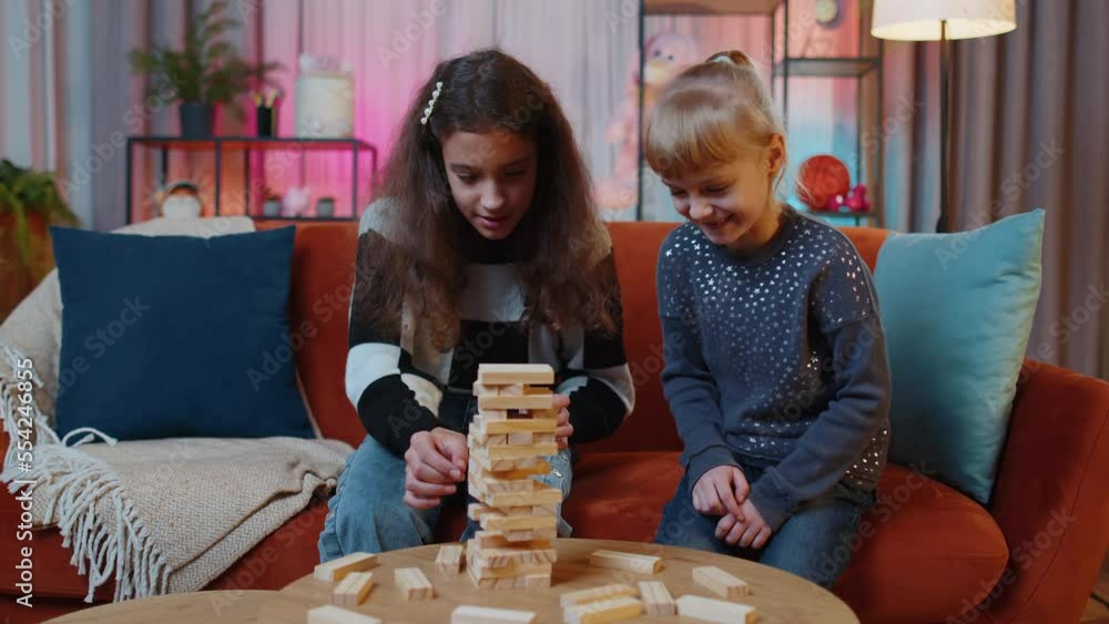 Teenage child and little sister kid girls build tower from wooden ...