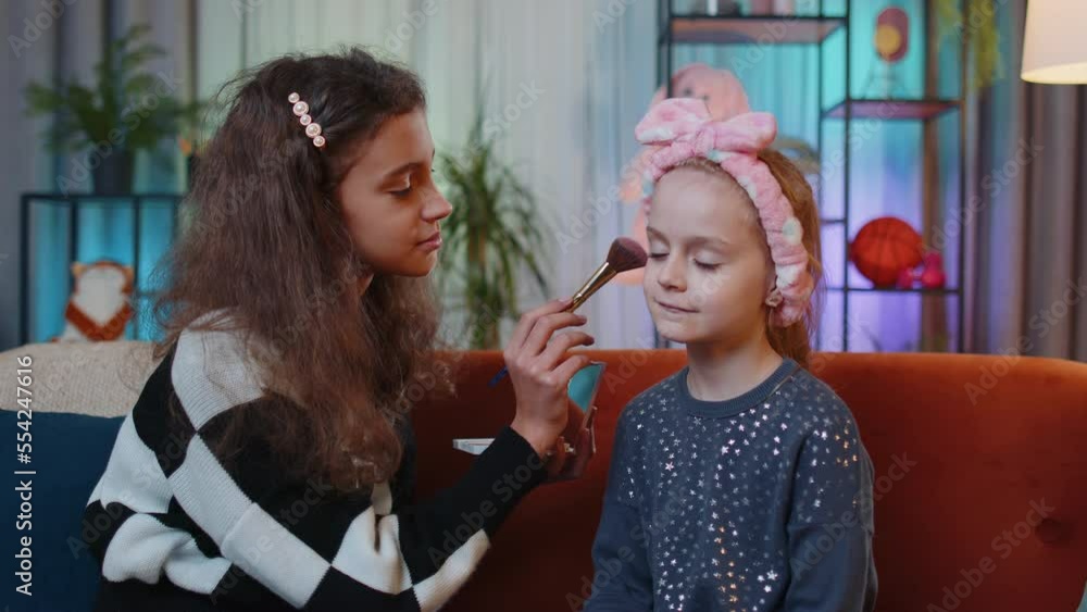 Vídeo do Stock: Teenage child helps or teaches to do face makeup her ...