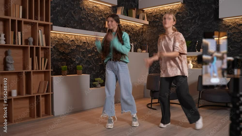 Two pretty girls filming their rhythmic synchronized dance moves. Young ...