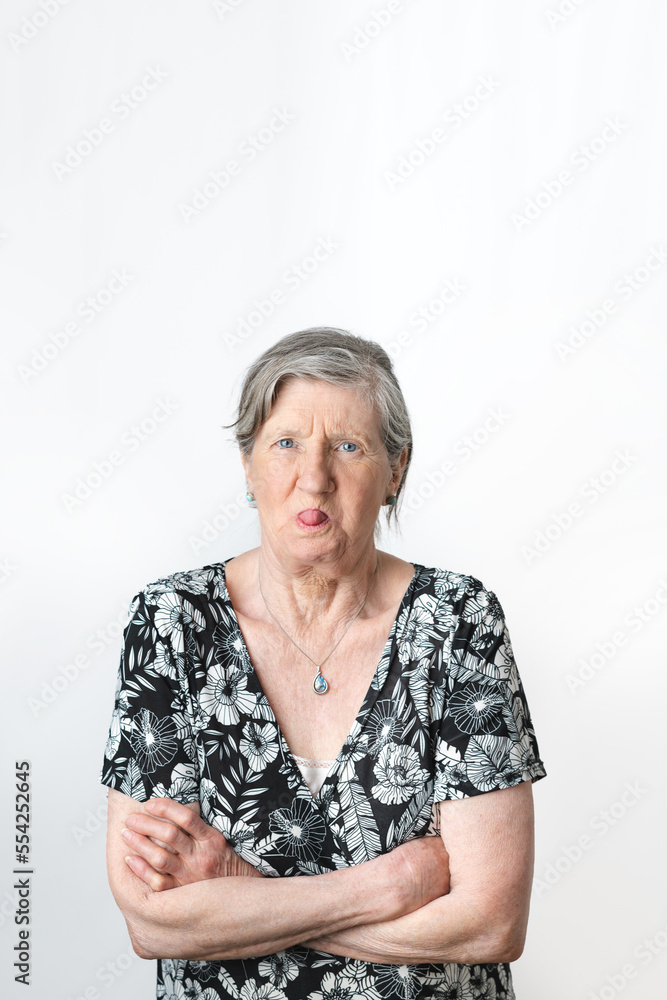 Old senior grey-haired woman doing mocking gesture while sticking out ...