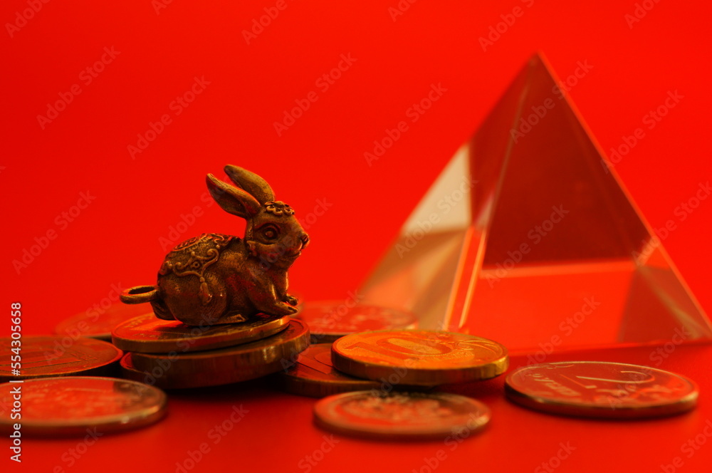Rabbit figurine with coins on a red background. Financial symbol. The ...