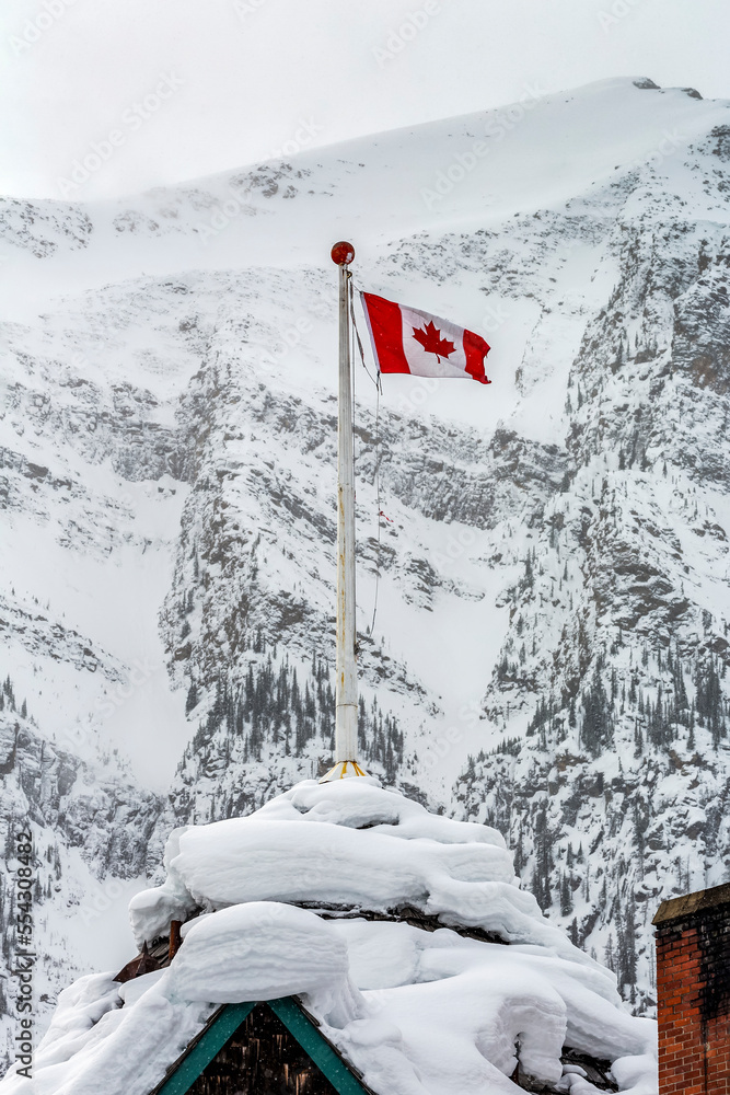 Close up of snow-covered building peak with a Canadian flag and a snow ...