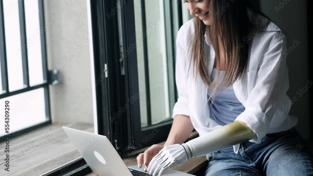 Motivated woman using prosthetic arm working or learning notebook ...