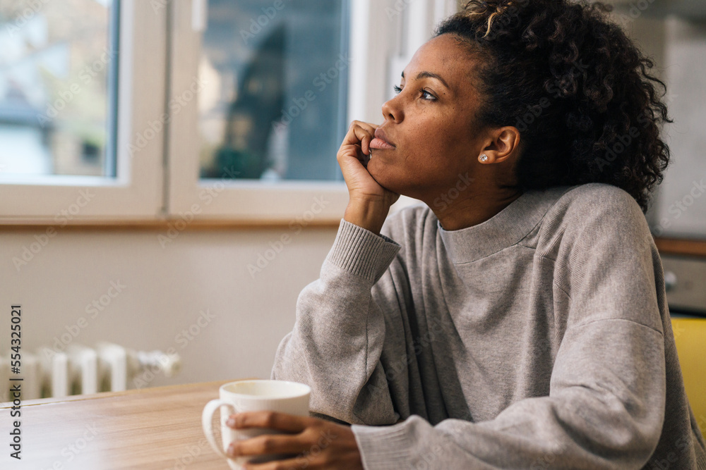 Beautiful woman is sitting alone in the kitchen and thinking Stock ...
