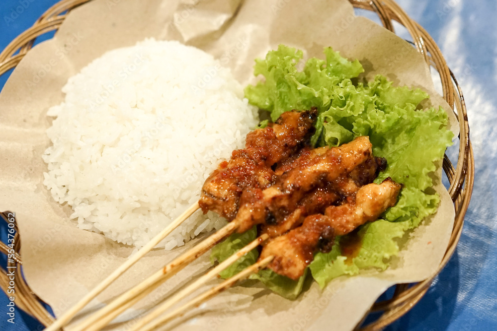 Red chicken satay legend with rice and vegetable salad. Sate Ayam ...
