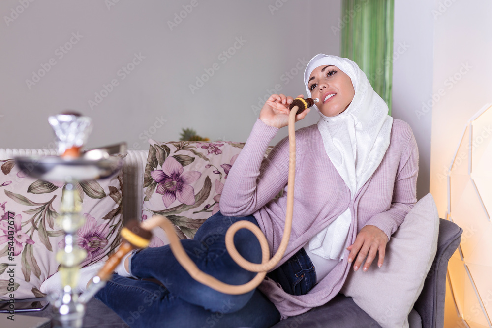 Muslim woman smoking shisha at home. Muslim young woman enjoying while ...