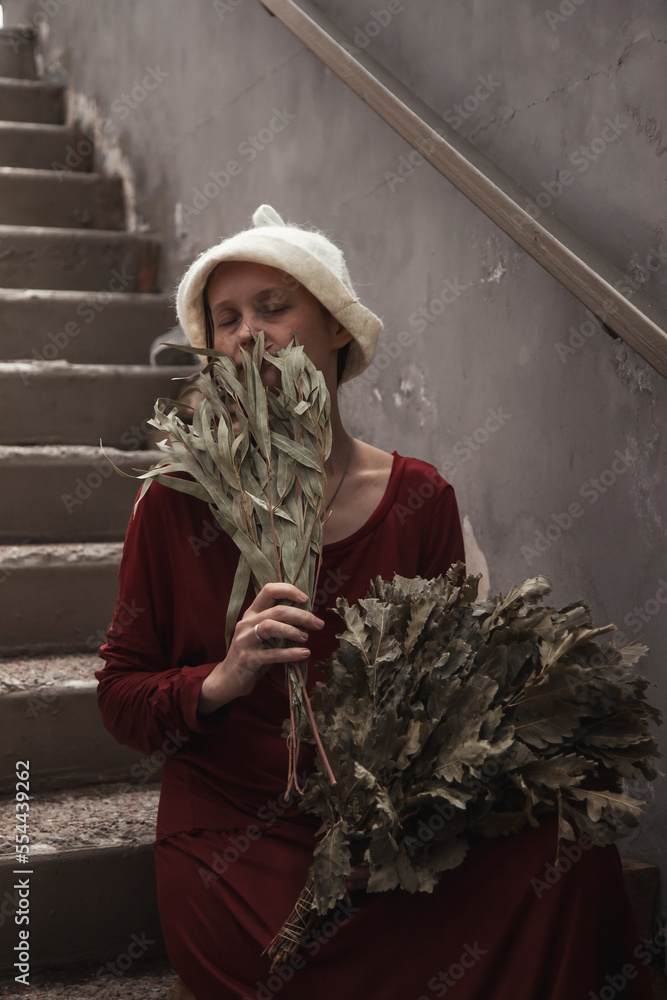 Russian bathhouse. Woman in traditional dress and hat with bath brooms ...