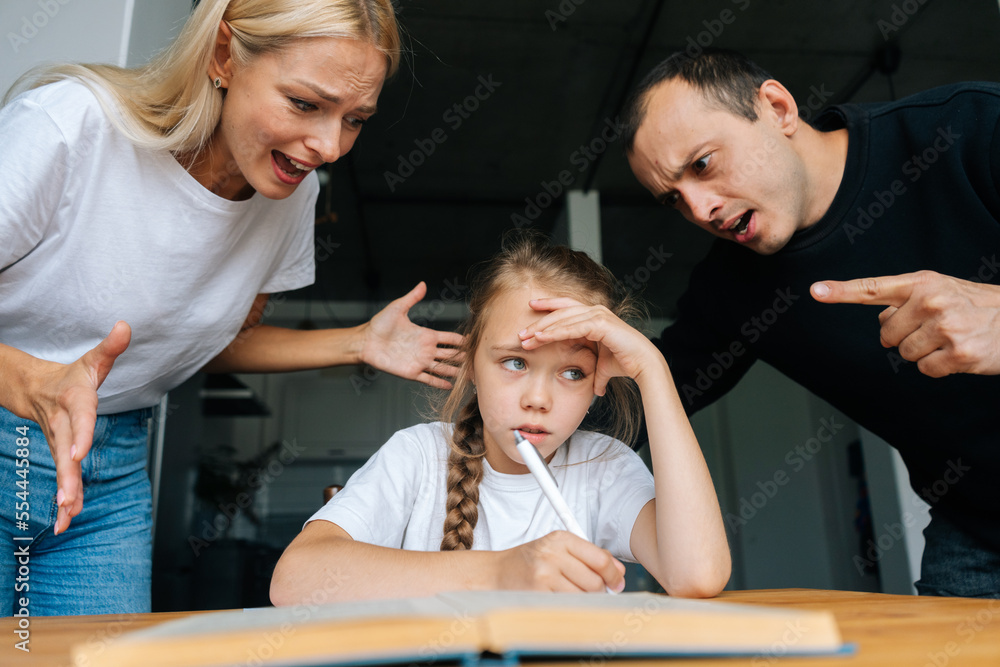 Portrait of tired little girl doing homework sitting at desk at home on ...