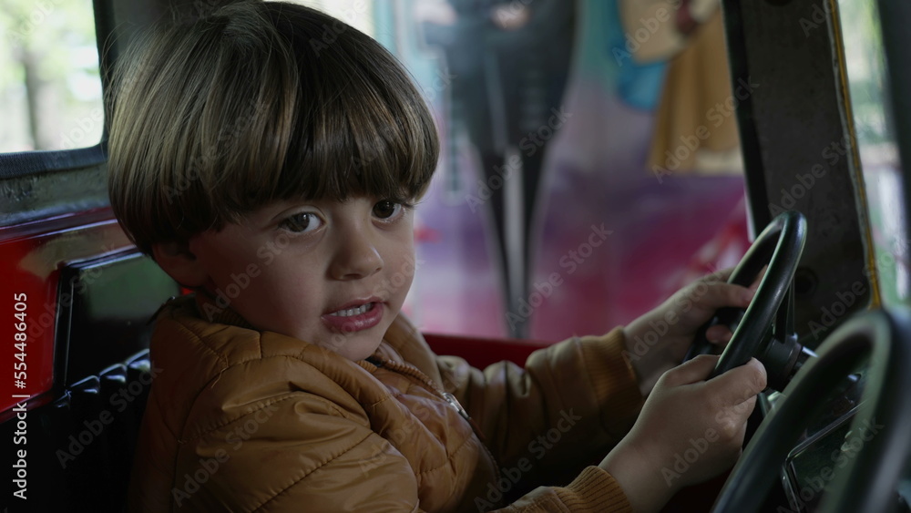 One happy small boy driving toy car interior at amusement park carousel ...