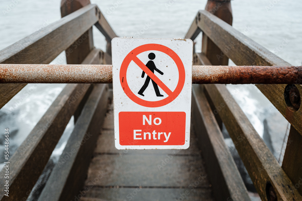 Shallow focus of a No Entry sign seen at the entrance to a wooden pier ...