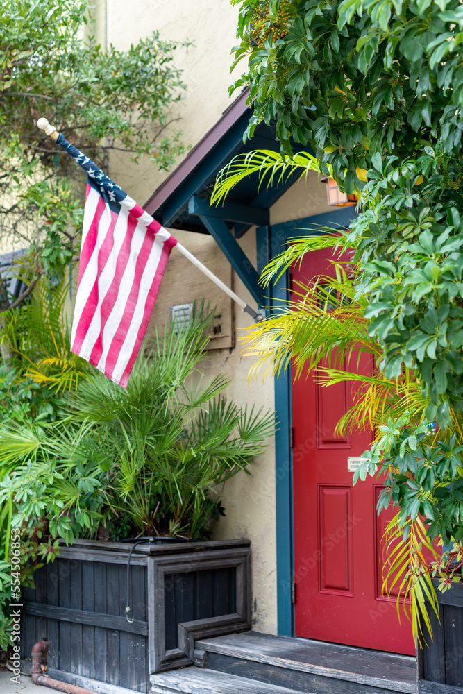 A red colorful door with blue trim in a white colored house. There's a ...
