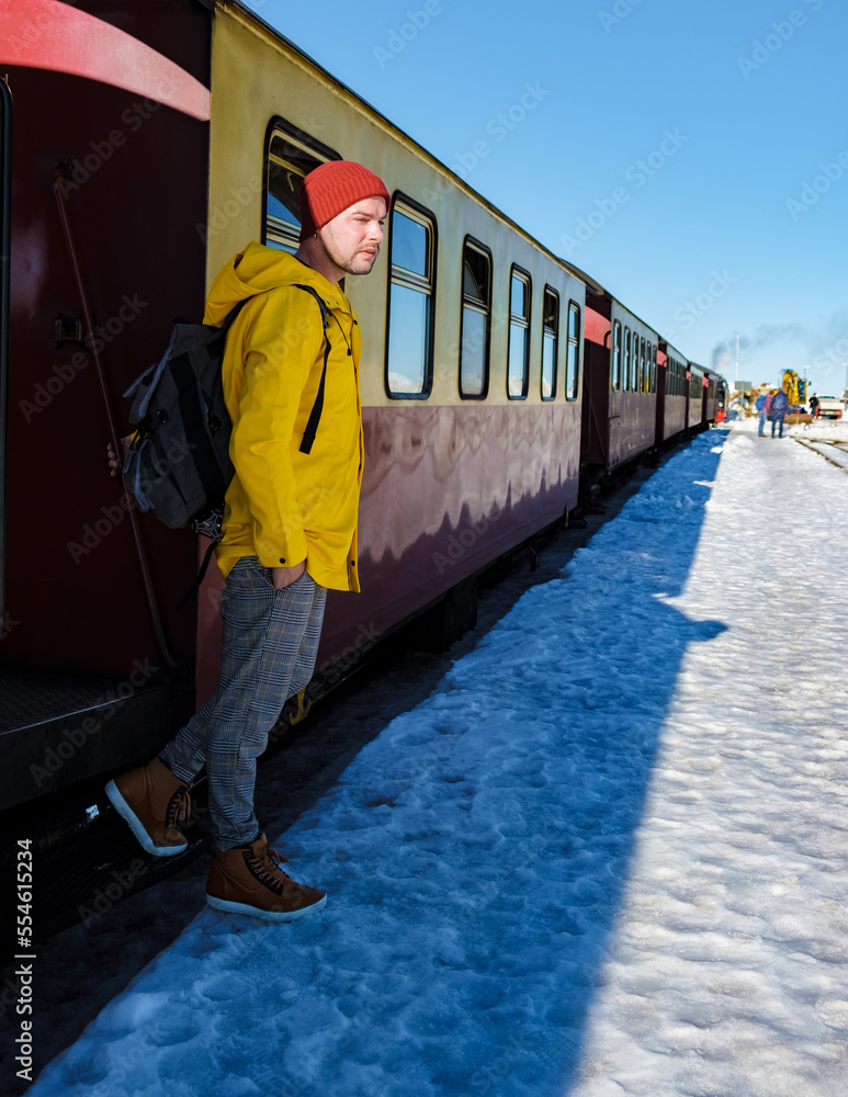 young men in rainjacket at the steam train during winter in the snow in ...