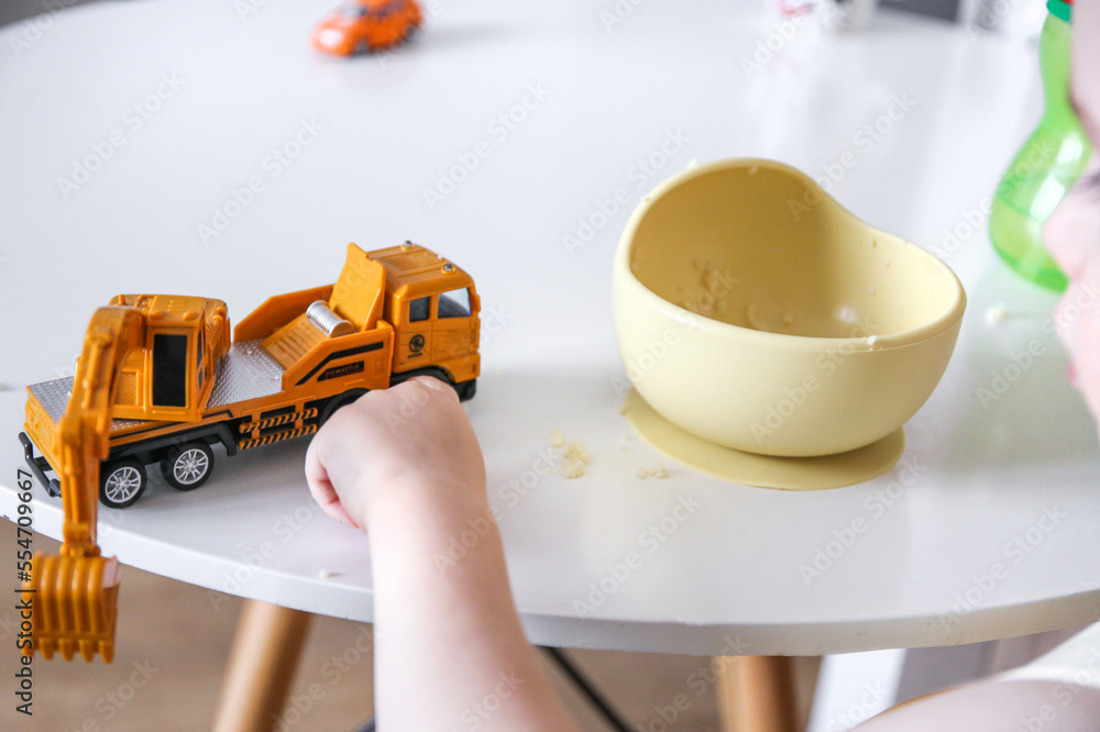 happy child eats at the table on his own. Healthy food, the boy feeds ...