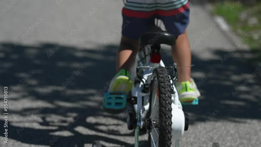 Back one small boy riding bicycle wearing helmet. Child rides bike in ...