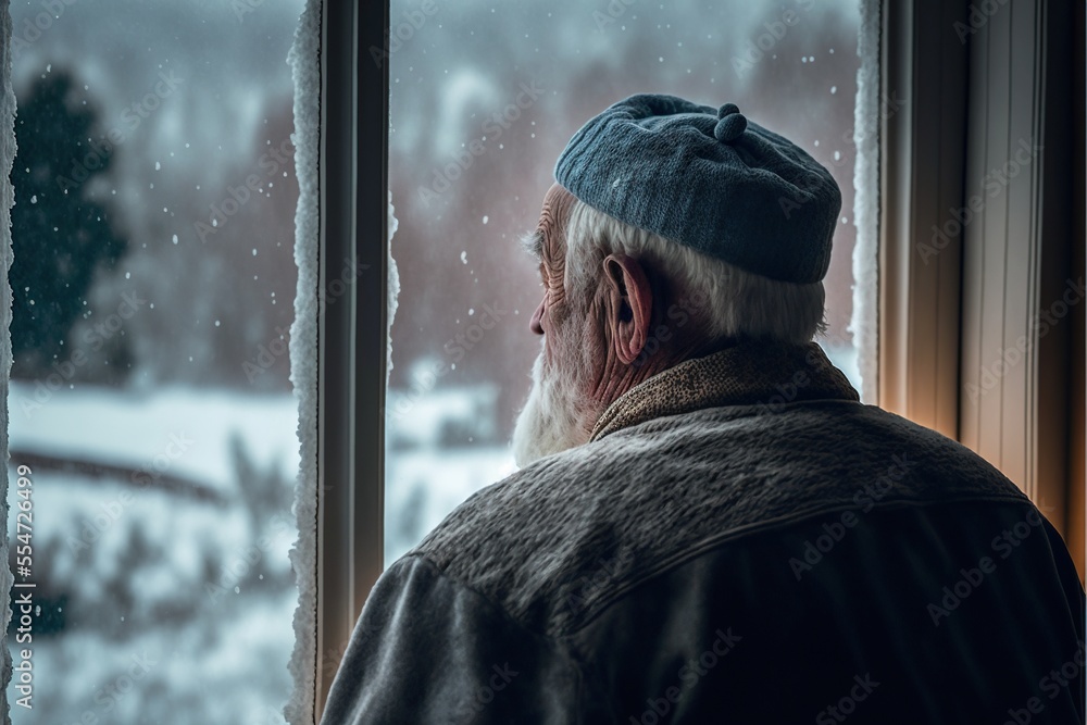 Lonely old man looks out the window at the first winter snow, back view ...