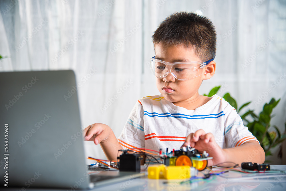 Asian kid boy assembling wheel into Arduino robot car homework, Little ...