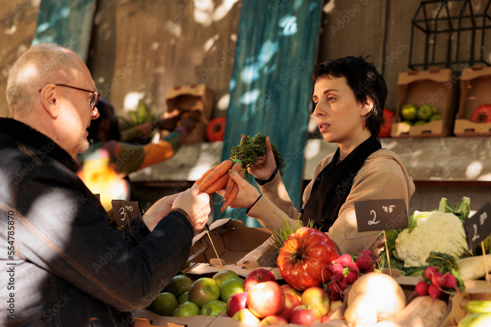 Caucasian happy farmer standing behind farmers market stand and showing ...