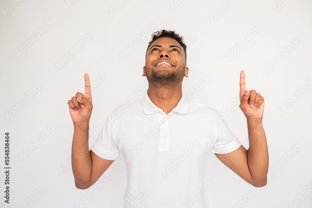 Cheerful young man pointing above at copyspace. Male Indian model with ...