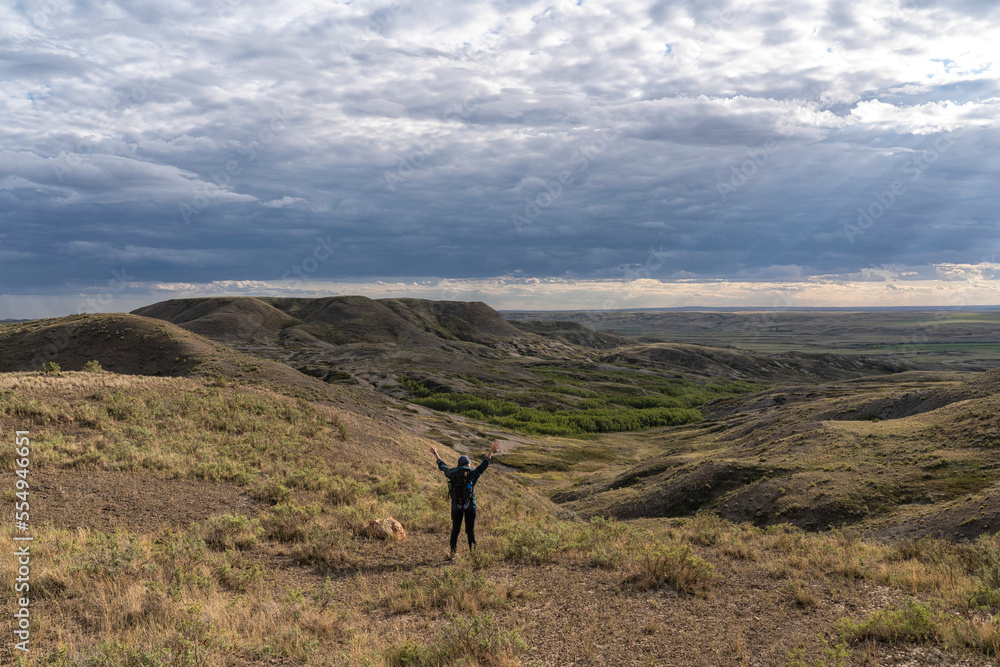 Woman standing with her arms raised while looking at a beautiful vista ...