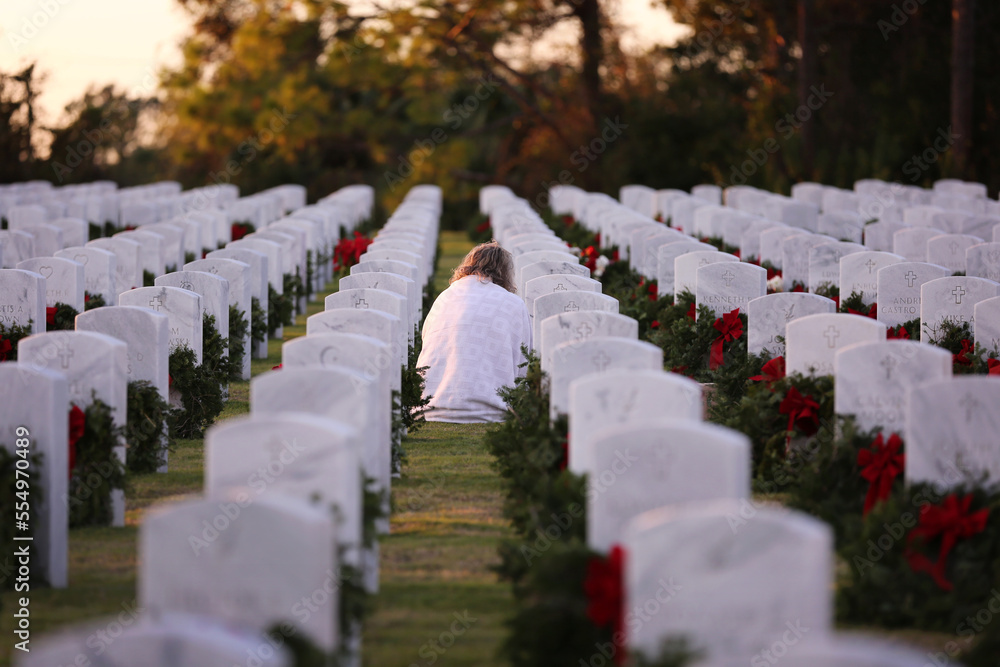 Widow grieving at her husband's grave at national cemetery, with ...