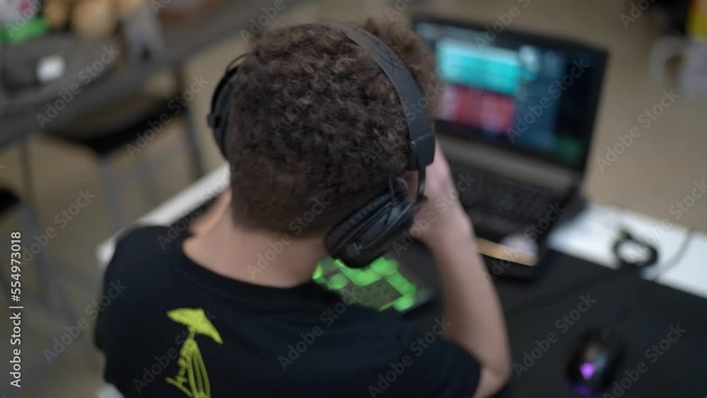 A teenage guy with curly hair plays emotionally a computer game on a ...