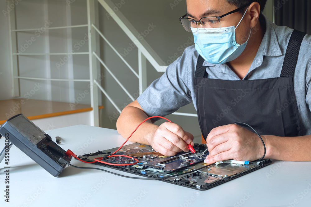 young man who is a computer technician A laptop motherboard repairman ...