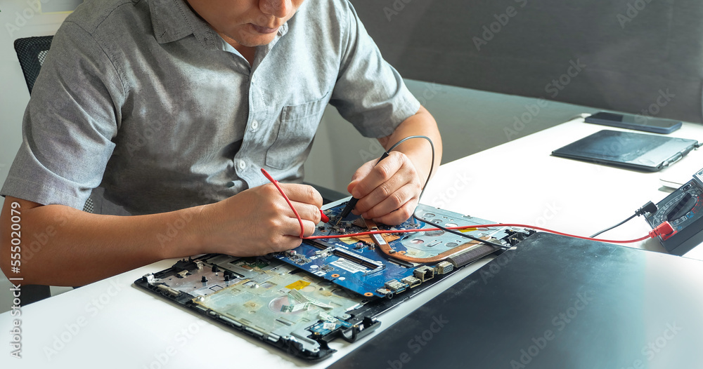 young man who is a computer technician A laptop motherboard repairman ...