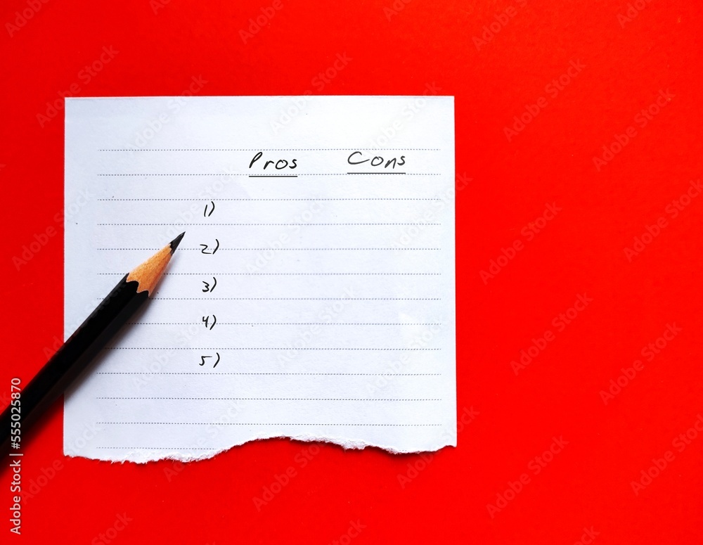 Pencil on note paper with text written PROS CONS and list number, means ...