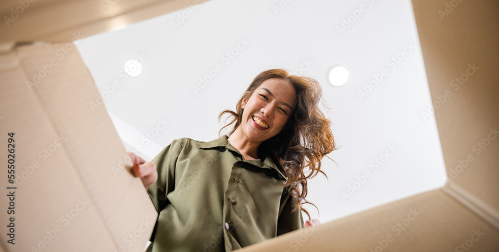 Happy Asian young woman opening carton box from internet store order ...