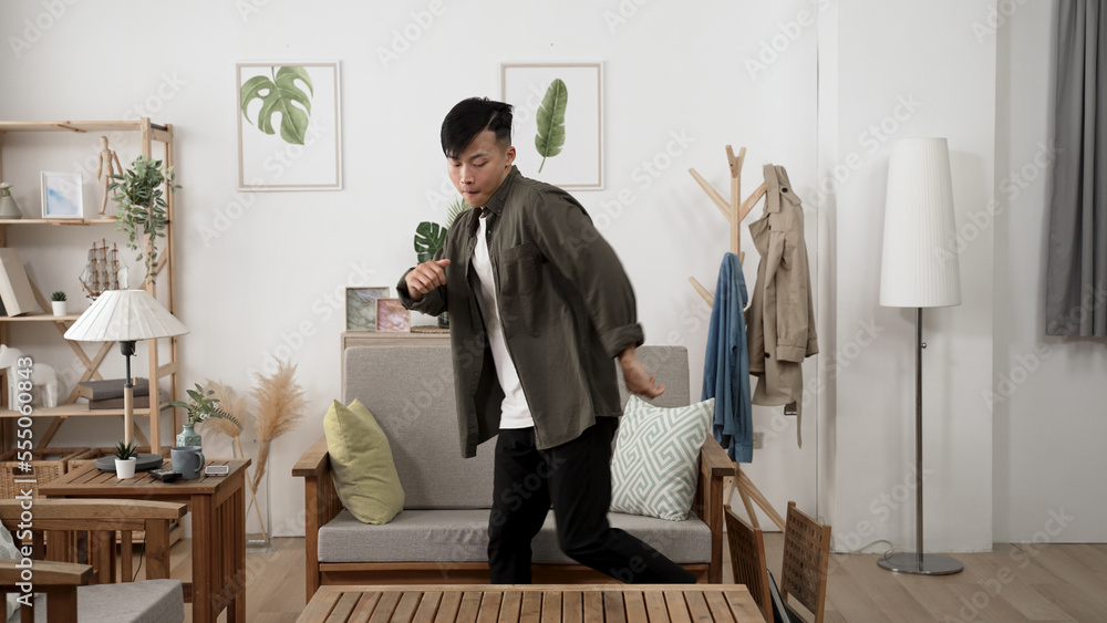 energetic asian young guy spinning in place while partying alone with ...