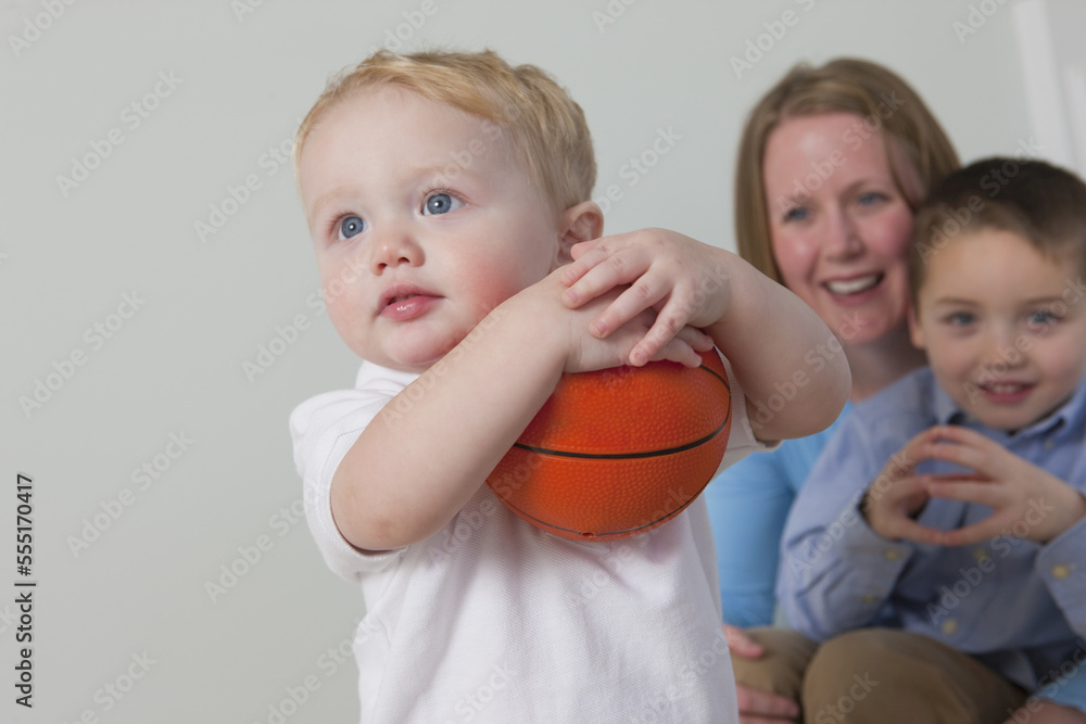 Baby boy holding a ball with his brother signing the word 'Ball' in ...