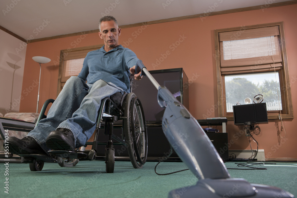 Man with spinal cord injury in a wheelchair using a vacuum cleaner at ...