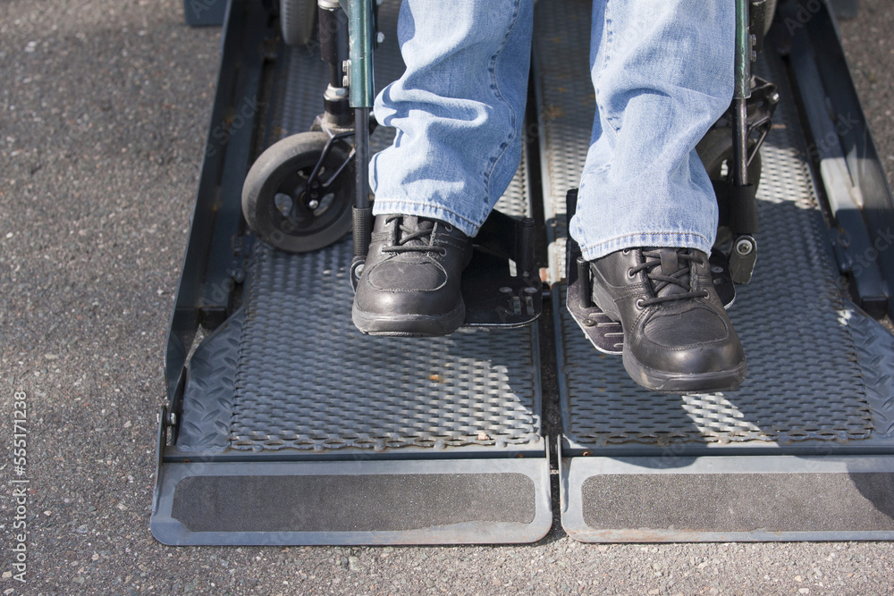 Legs of a man with spinal cord injury in a wheelchair on accessible van ...