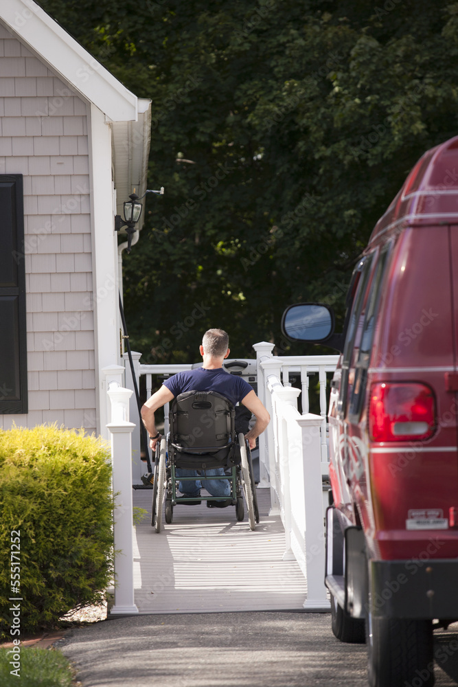 Man with spinal cord injury in a wheelchair going up home ramp Stock ...