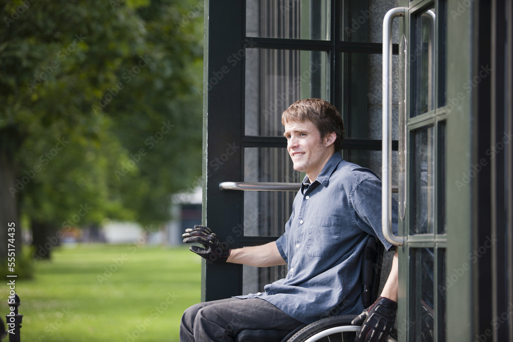 Man with spinal cord injury in a wheelchair exiting door of public ...