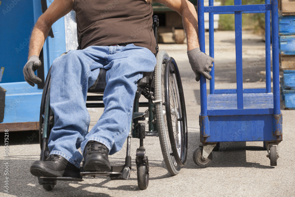 Loading dock worker with spinal cord injury in a wheelchair moving a ...