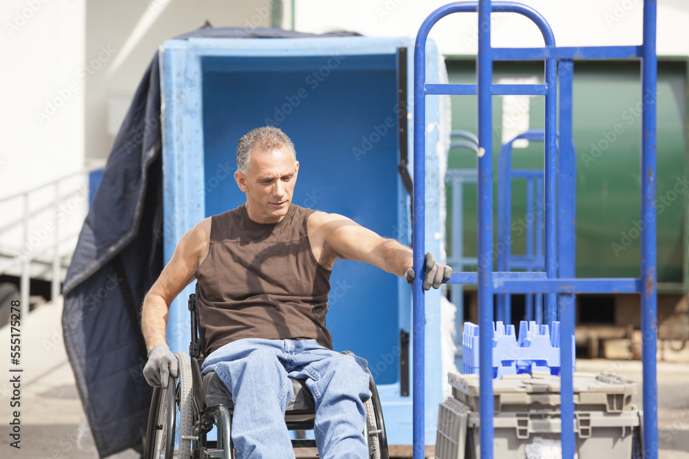 Loading dock worker with spinal cord injury in a wheelchair moving a ...