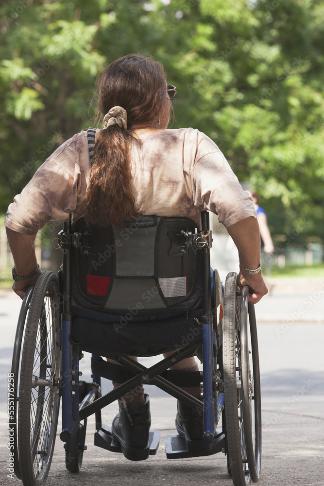Woman with spinal cord injury crossing street at accessible access ...