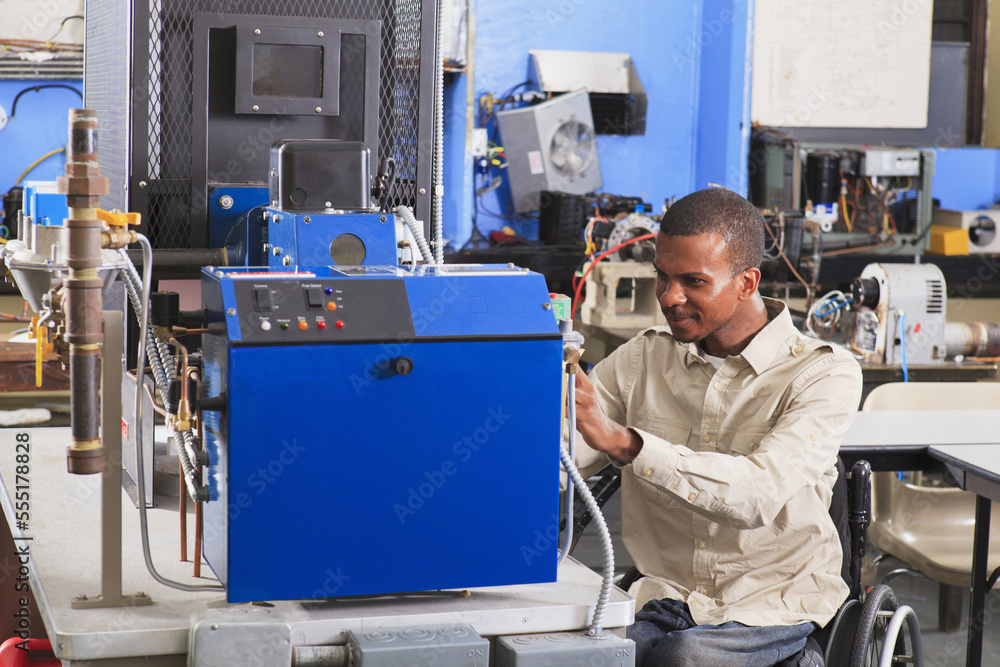 Student in wheelchair studying natural gas fuel line on furnace in HVAC ...