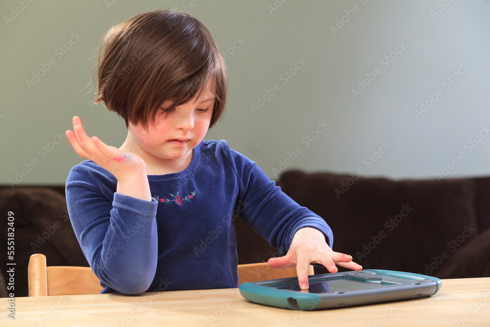 Little girl with Down Syndrome playing an electronic learning game ...