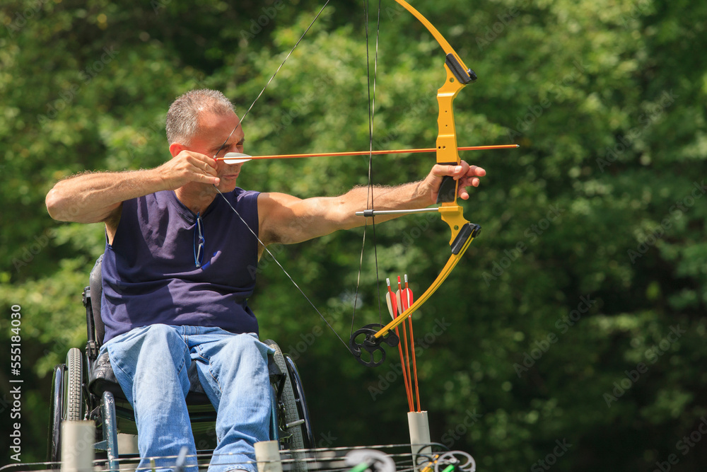Man with spinal cord injury in wheelchair aiming his bow and arrow for ...