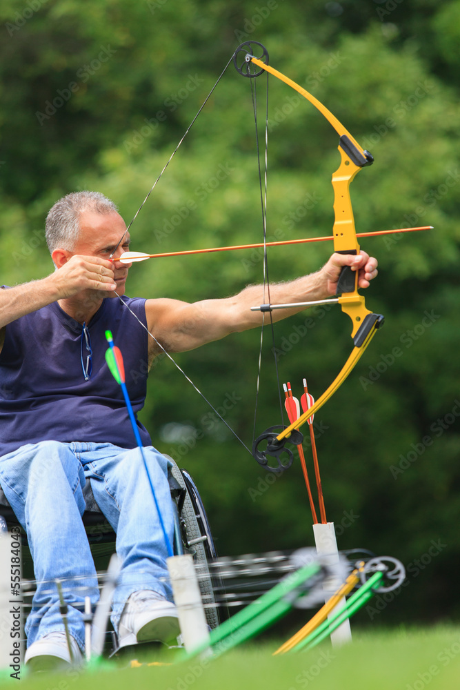 Man with spinal cord injury in wheelchair aiming his bow and arrow for ...