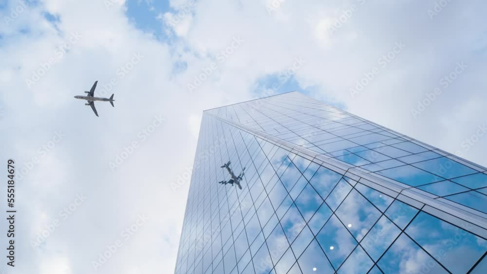 Airplane passing over glass business buildings of blue mirrors in low ...