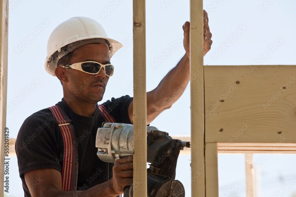 Carpenter using a nail gun at a construction site Stock Photo | Adobe Stock
