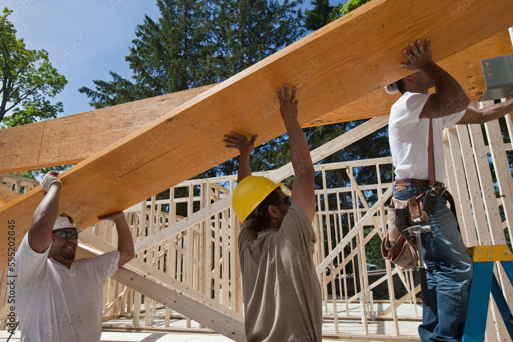 Carpenters lifting a laminated beam at a construction site Stock Photo ...