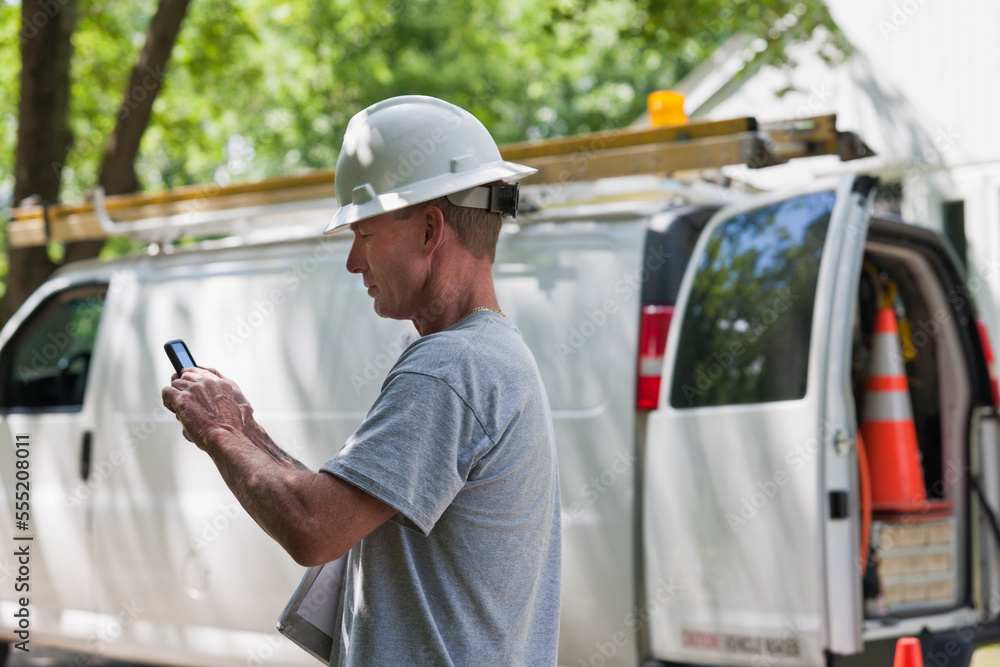 Cable installer reviewing work order for installation on smartphone ...