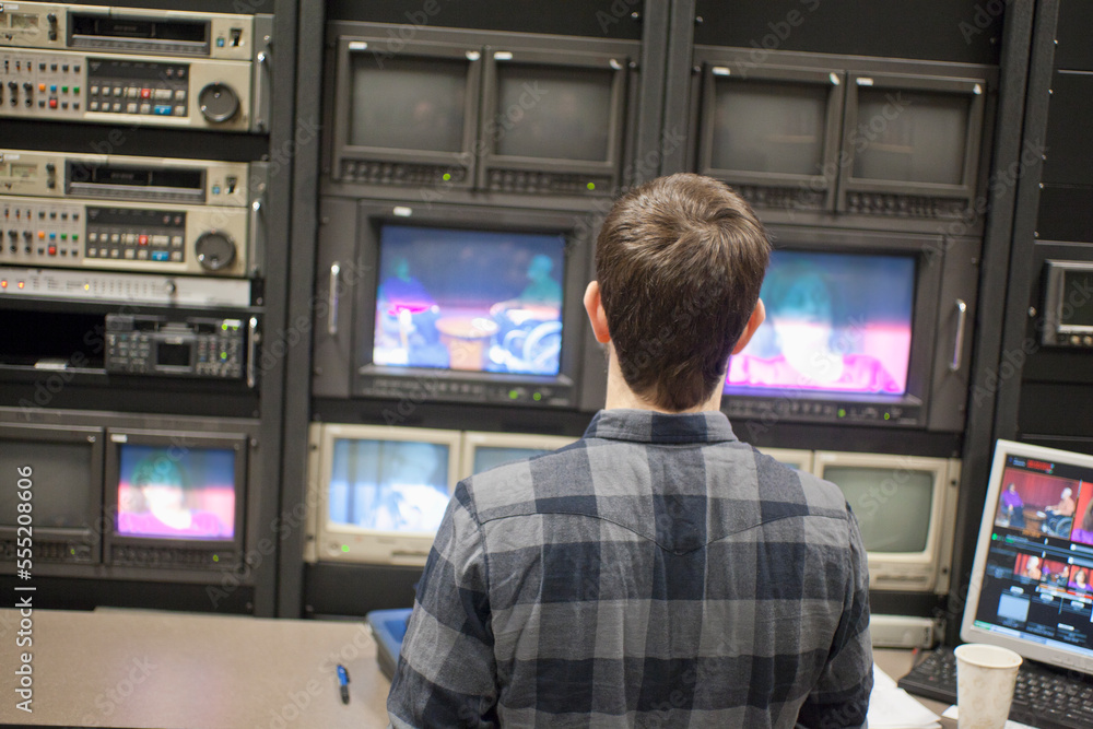 Video editor at work in a TV editing control room at a Cable TV Studio ...