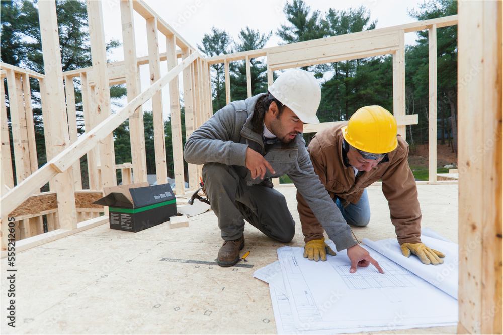 Construction supervisor reviewing home design plan with a carpenter ...