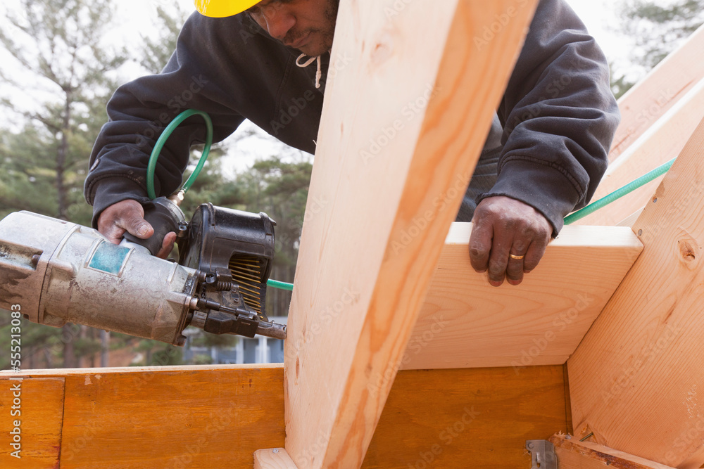 Carpenter with a nail gun on rafter braces Stock Photo | Adobe Stock