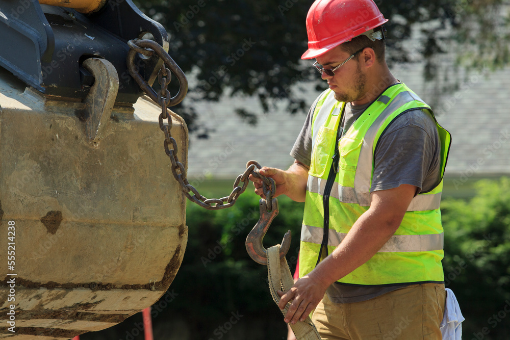 Construction worker attaching lifting strap to excavator bucket Stock ...